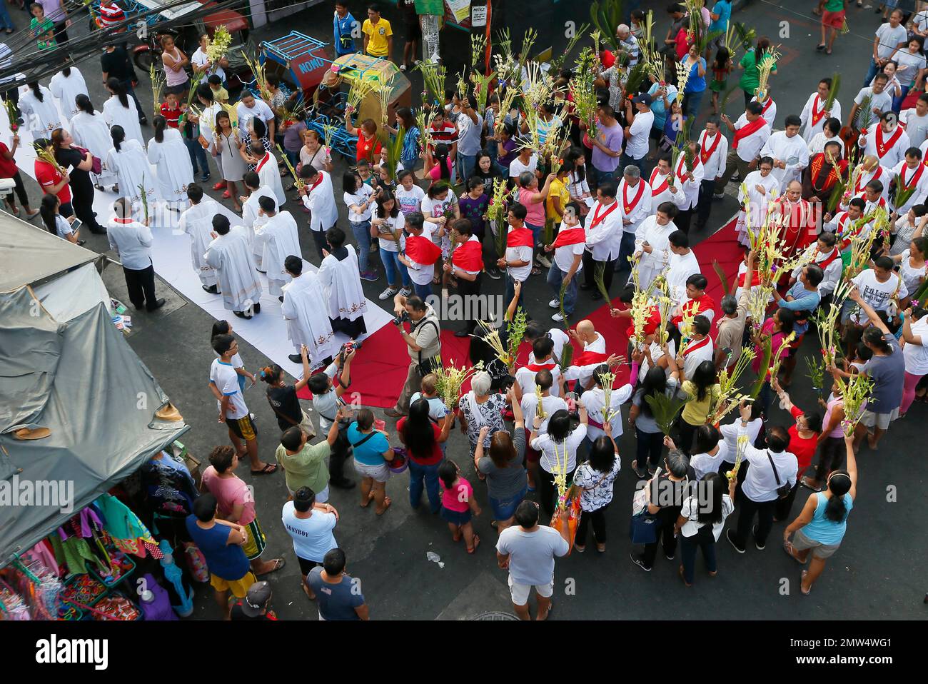 Devotees line up the route to have their palm fronds blessed with holy ...