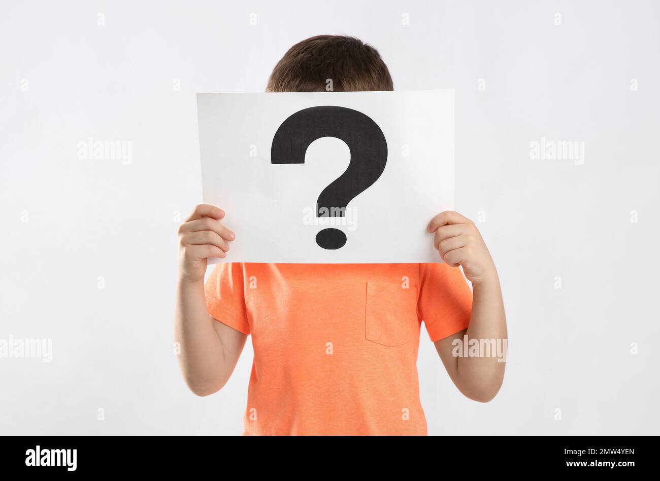 Little boy holding paper with question mark on white background Stock ...