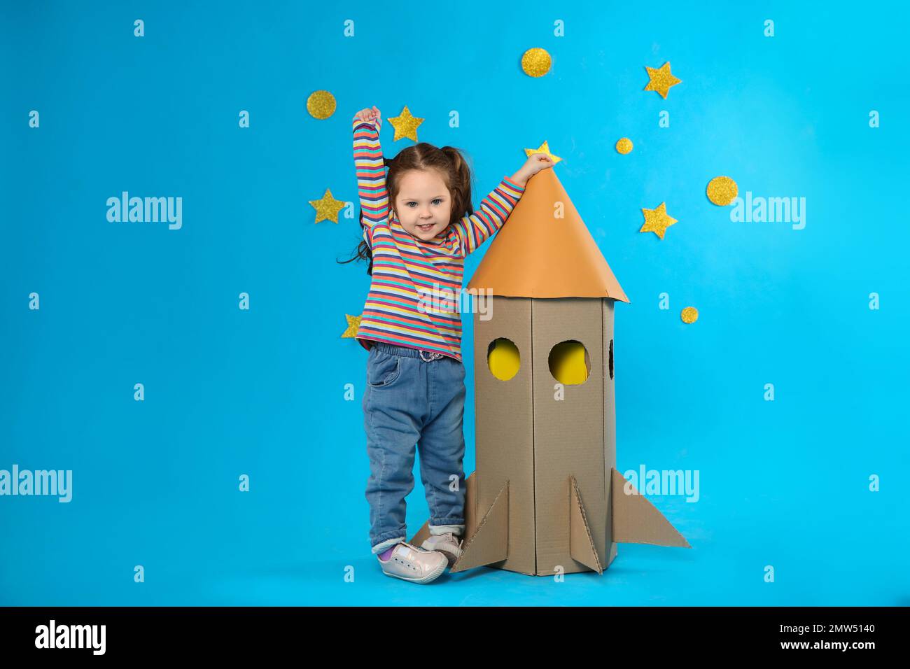 Little child playing with rocket made of cardboard box near stars on ...
