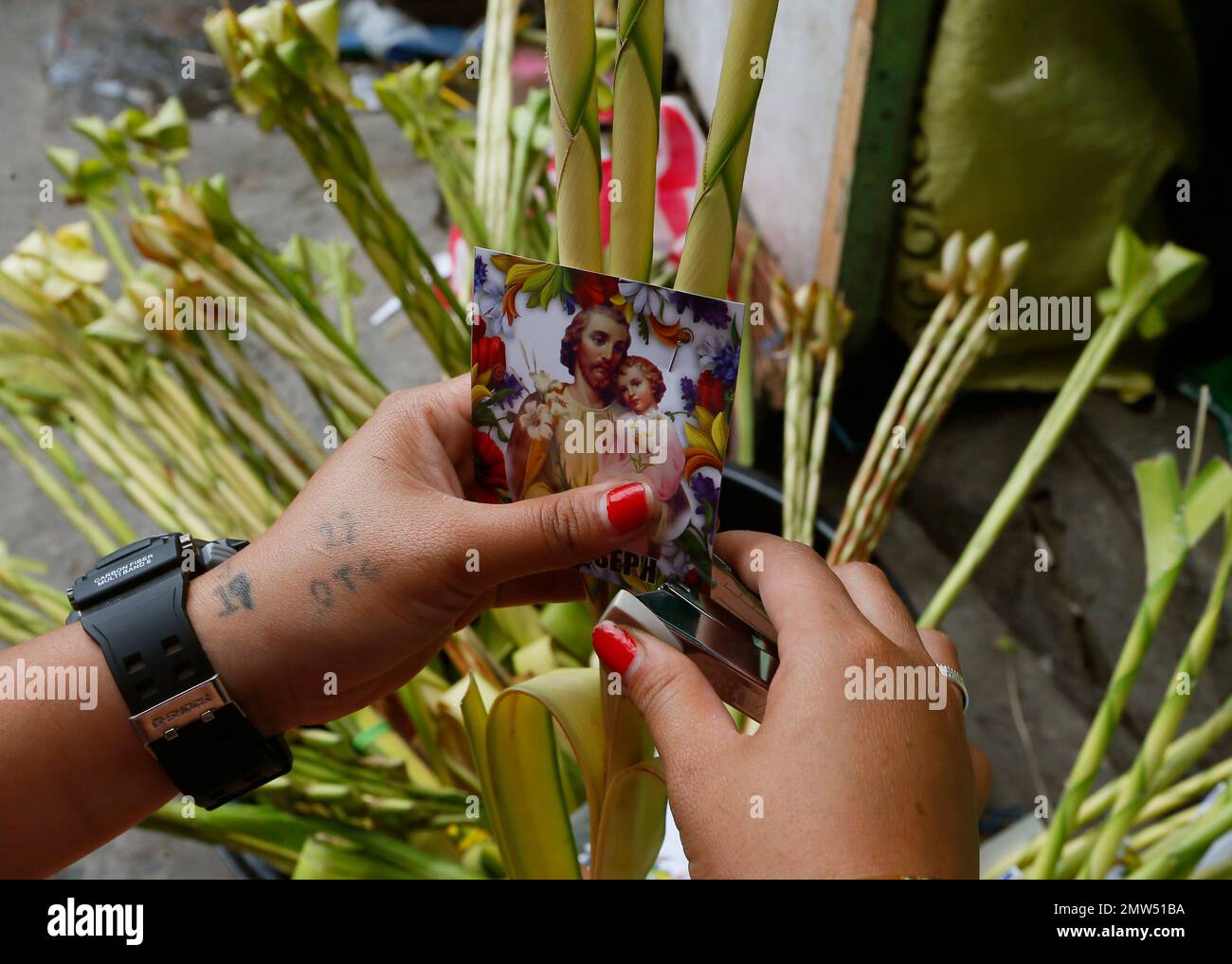 An enterprising resident staples an icon painting on palm fronds as the ...