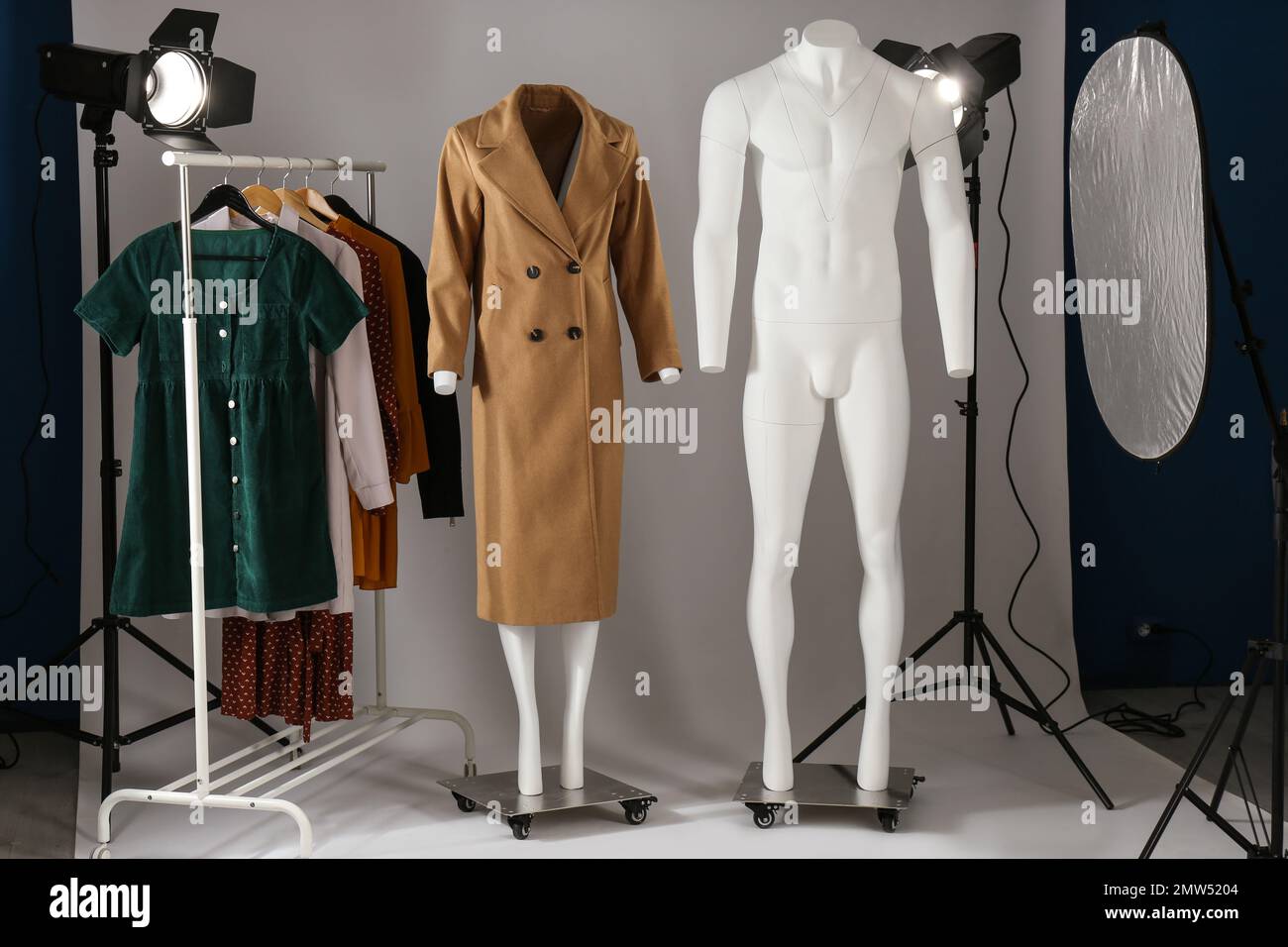 Ghost mannequins, clothes and professional lighting equipment in modern ...
