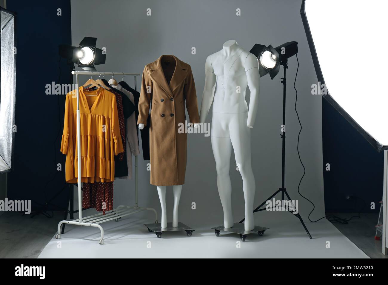 Ghost mannequins, clothes and professional lighting equipment in modern ...