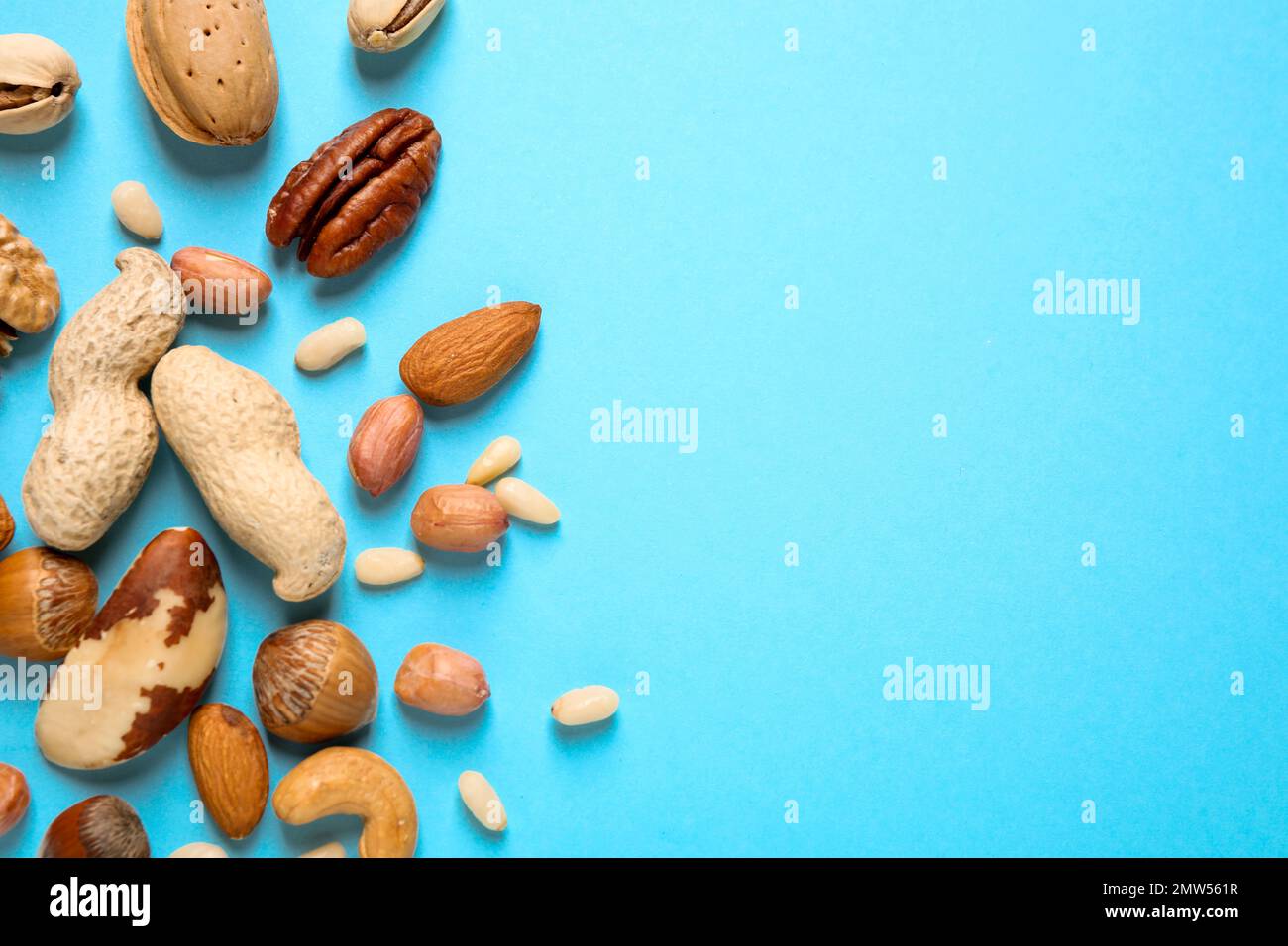 Different delicious nuts on light blue background, flat lay. Space for ...