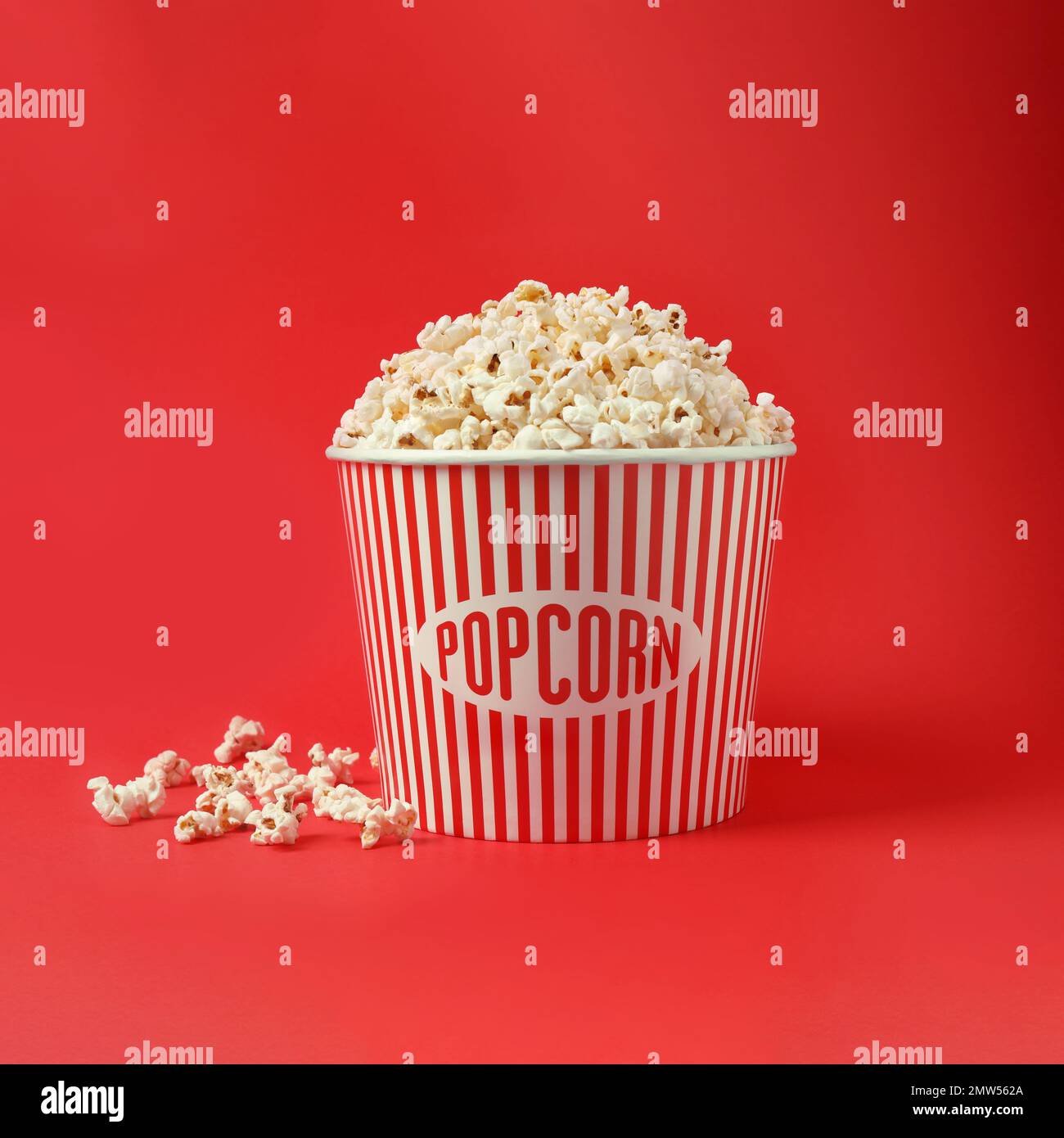 Delicious popcorn in paper bucket on red background Stock Photo - Alamy