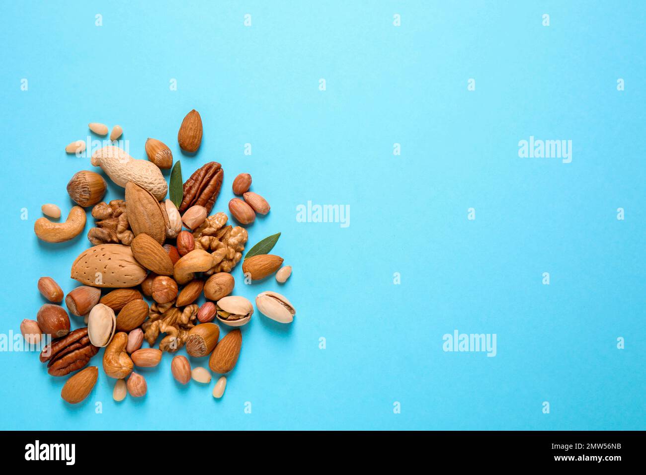 Different delicious nuts on light blue background, flat lay. Space for ...