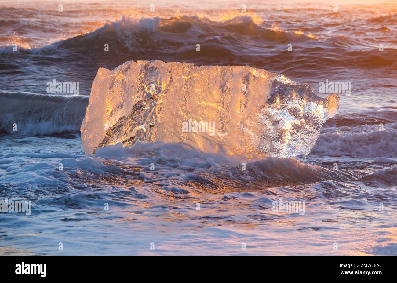 Pure Ice Shining on Black Volcanic Sand at Sunset, Ocean Waves Crash ...