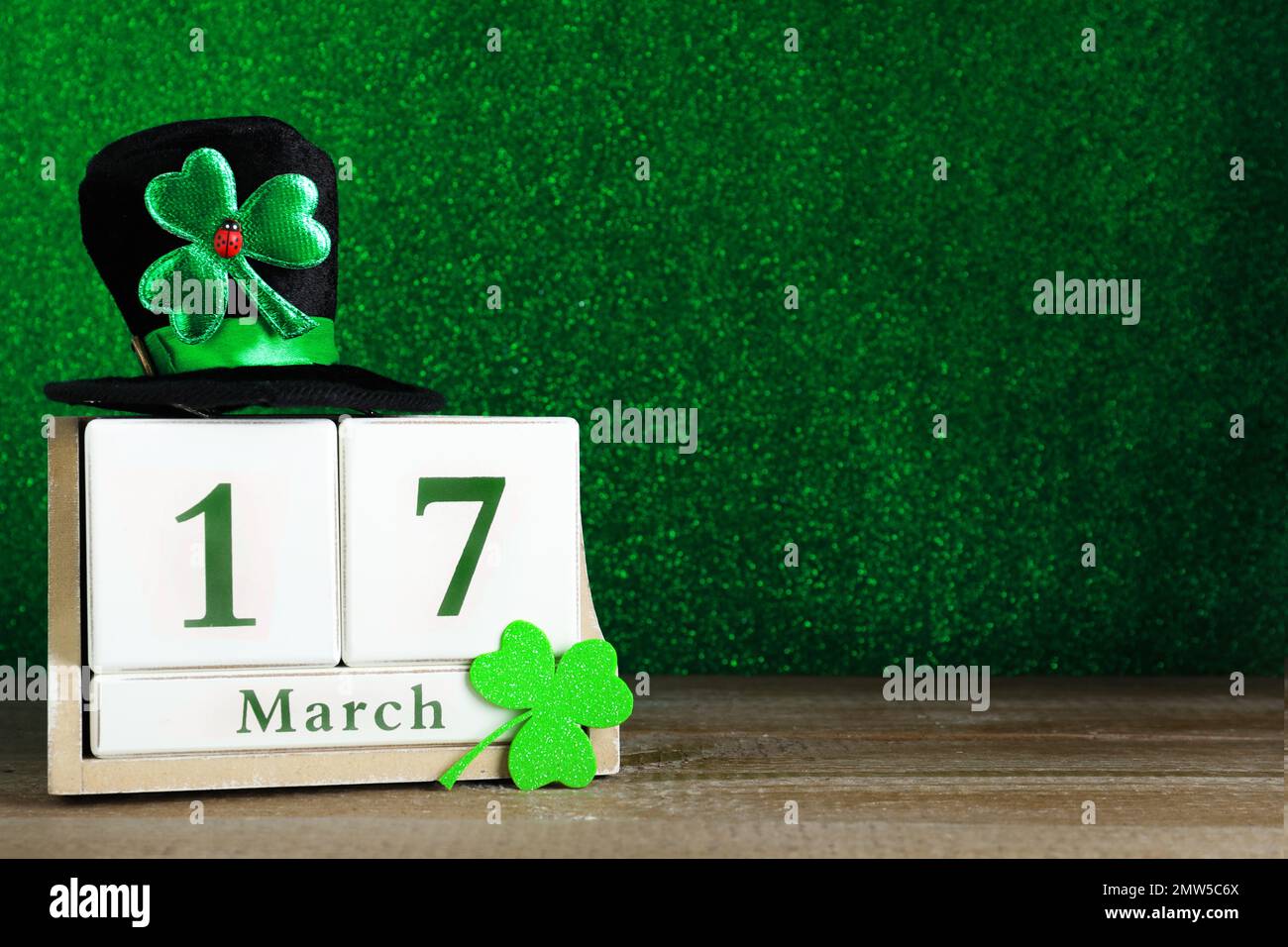 Black leprechaun hat, clover leaf and wooden block calendar on table ...