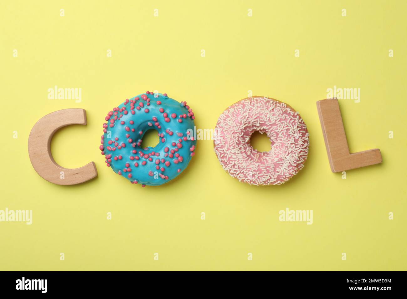 Word COOL made with wooden letters and donuts on yellow background ...