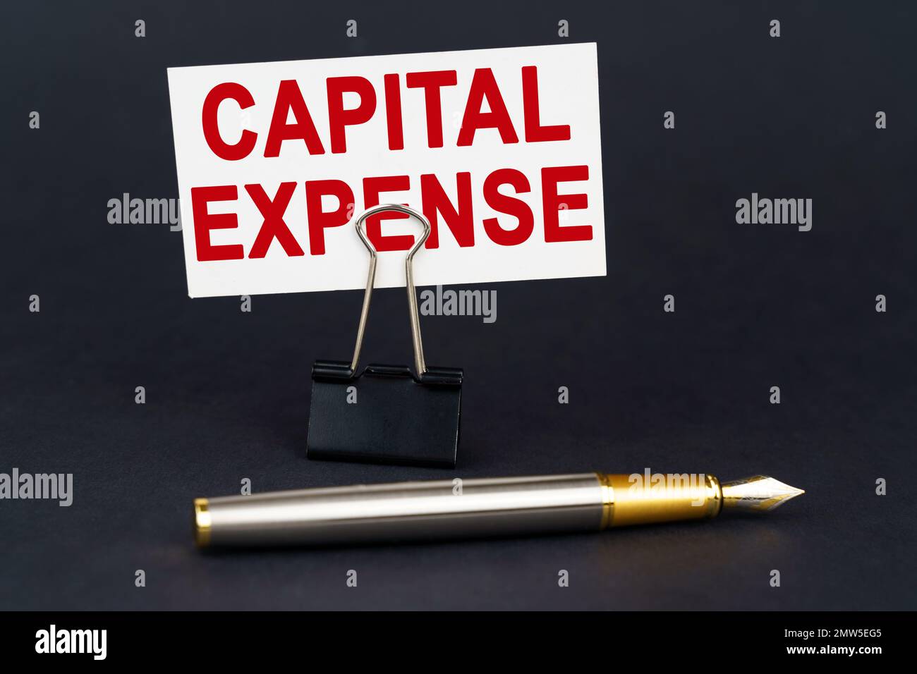 Business concept. On the black surface is a pen, an office paper clip ...