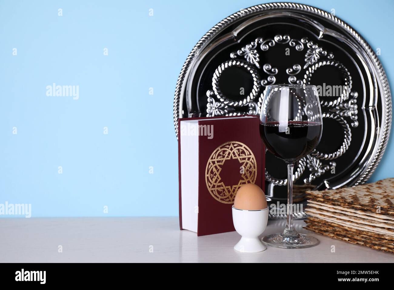 Symbolic Pesach (Passover Seder) items on table against light blue ...