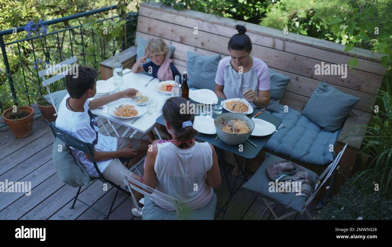 People eating lunch at house wooden patio outdoors. Children and two ...