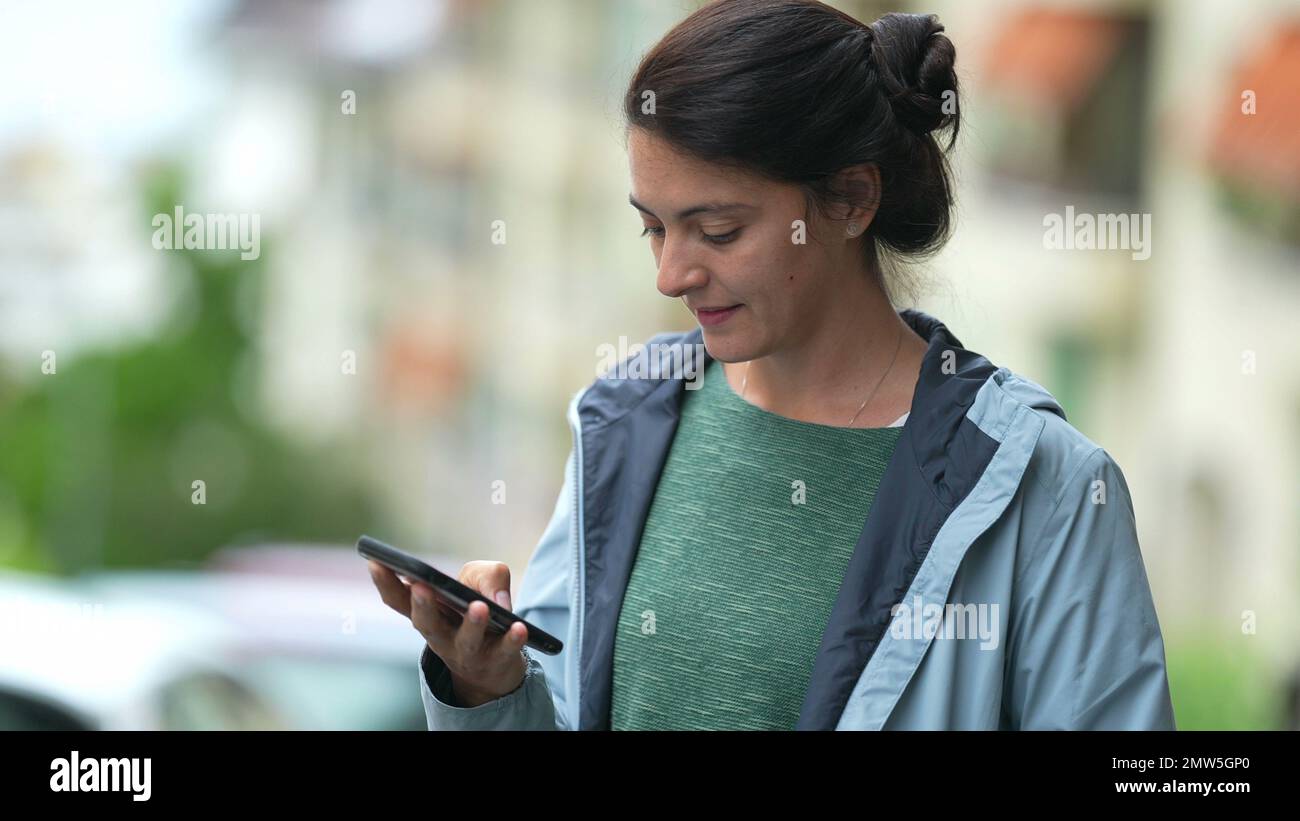 Perosn ending phone call. Woman standing outside in city street turns ...