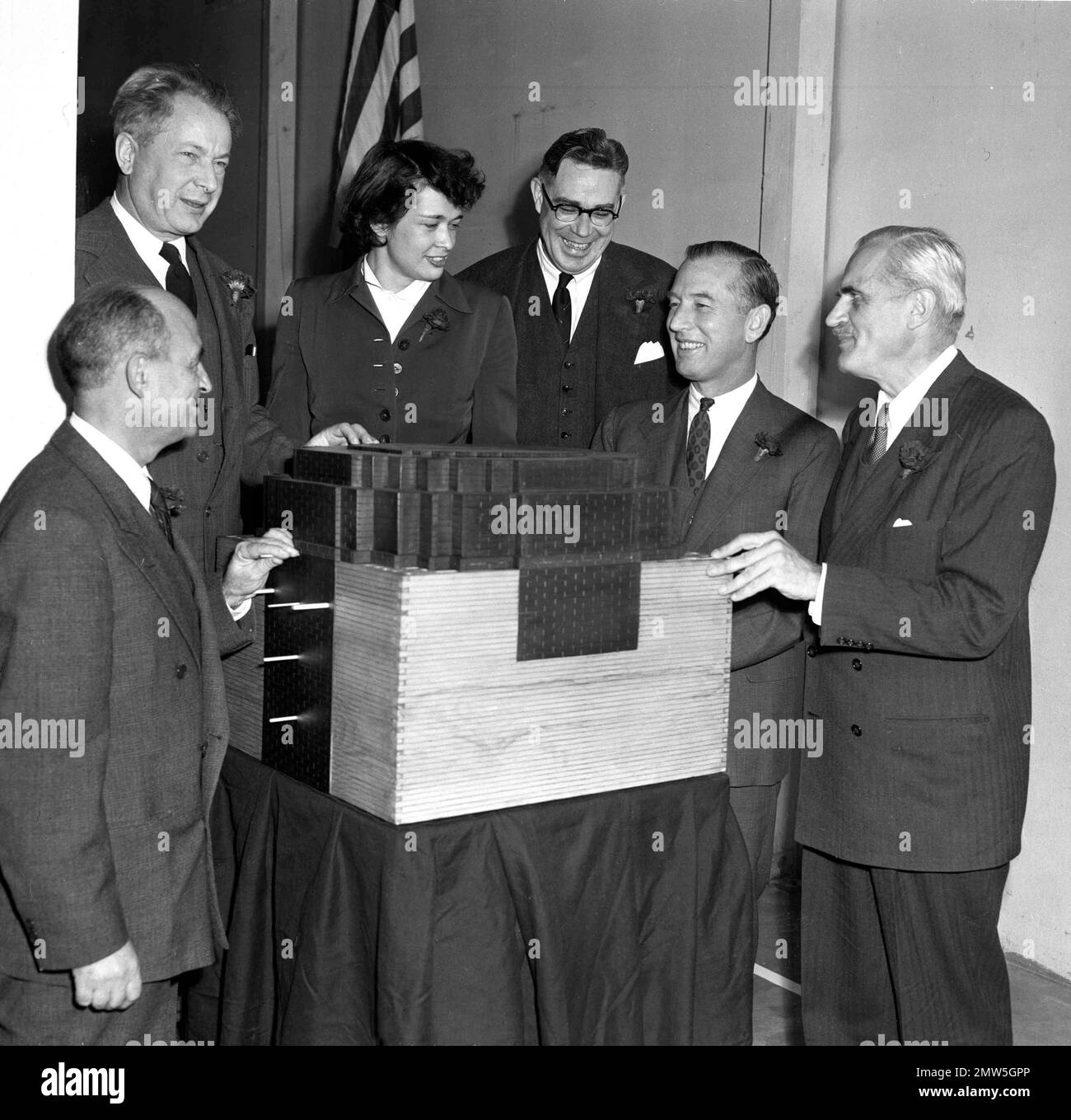 A group of scientists stand around model of first atomic pile at the ...