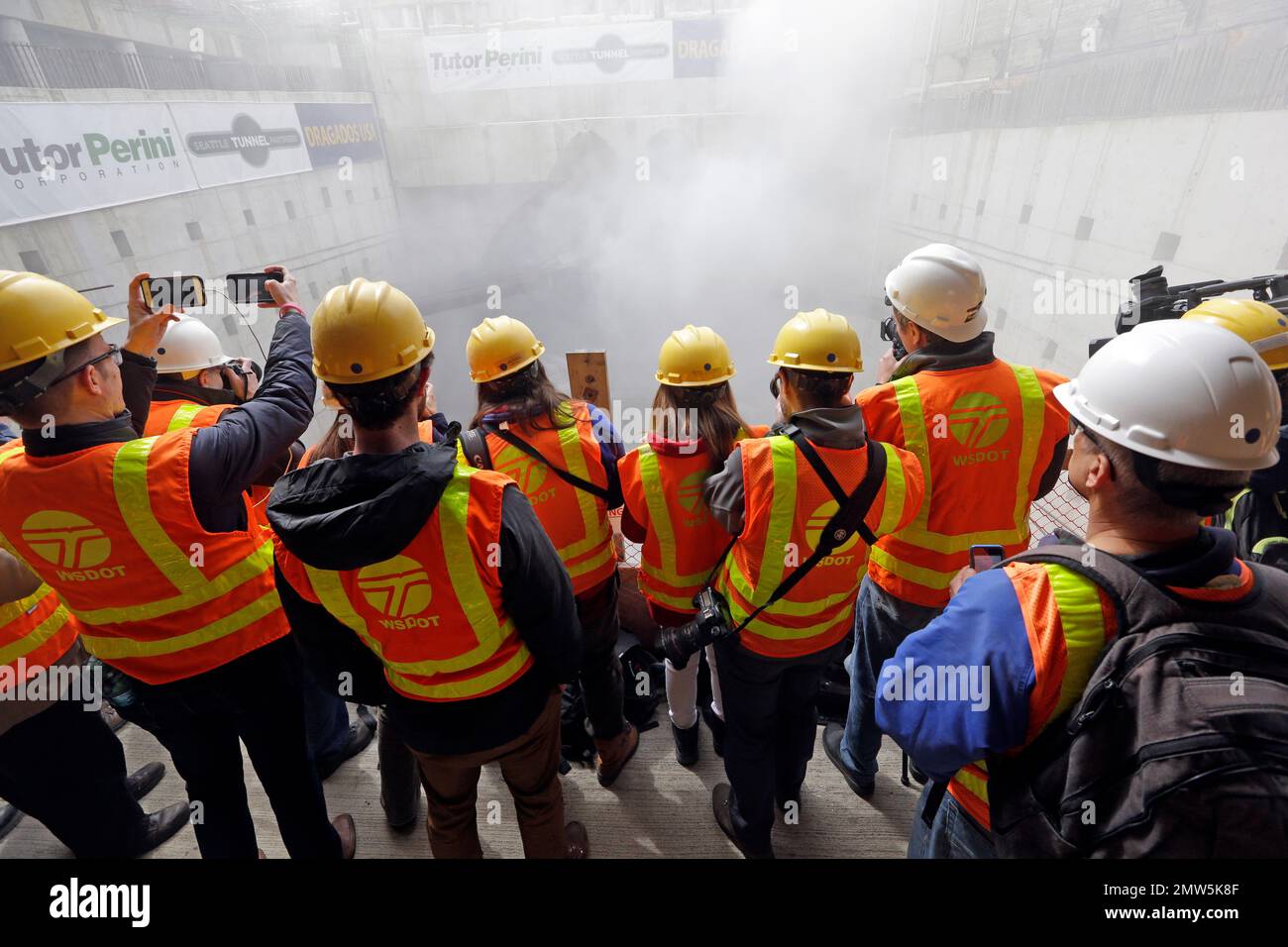 Media members look on as a cloud of concrete dust and water vapor fills ...