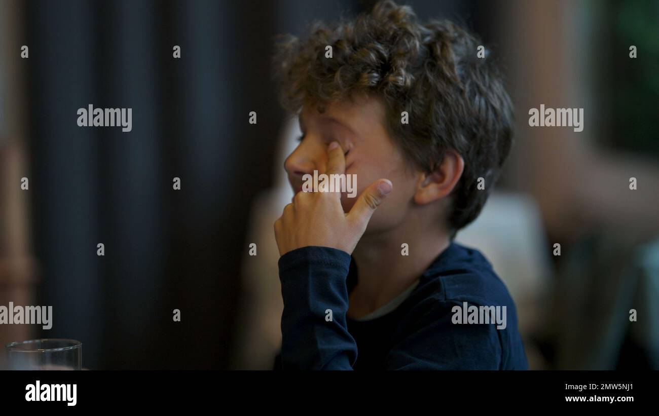 Young boy scratches eye with finger Stock Photo - Alamy