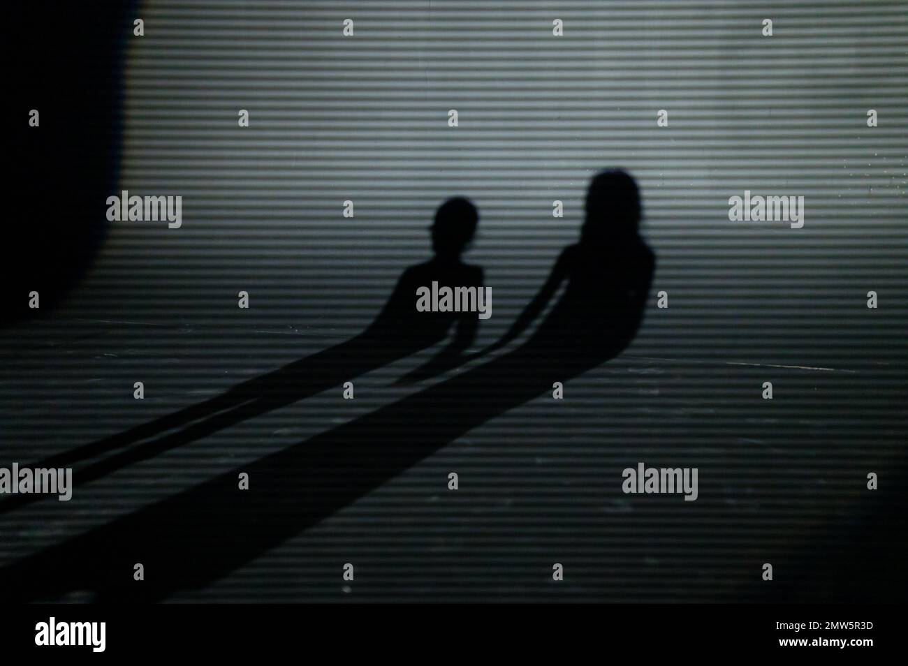 kid's shadows on wall. shadow of two children, boy and girl on striped ...