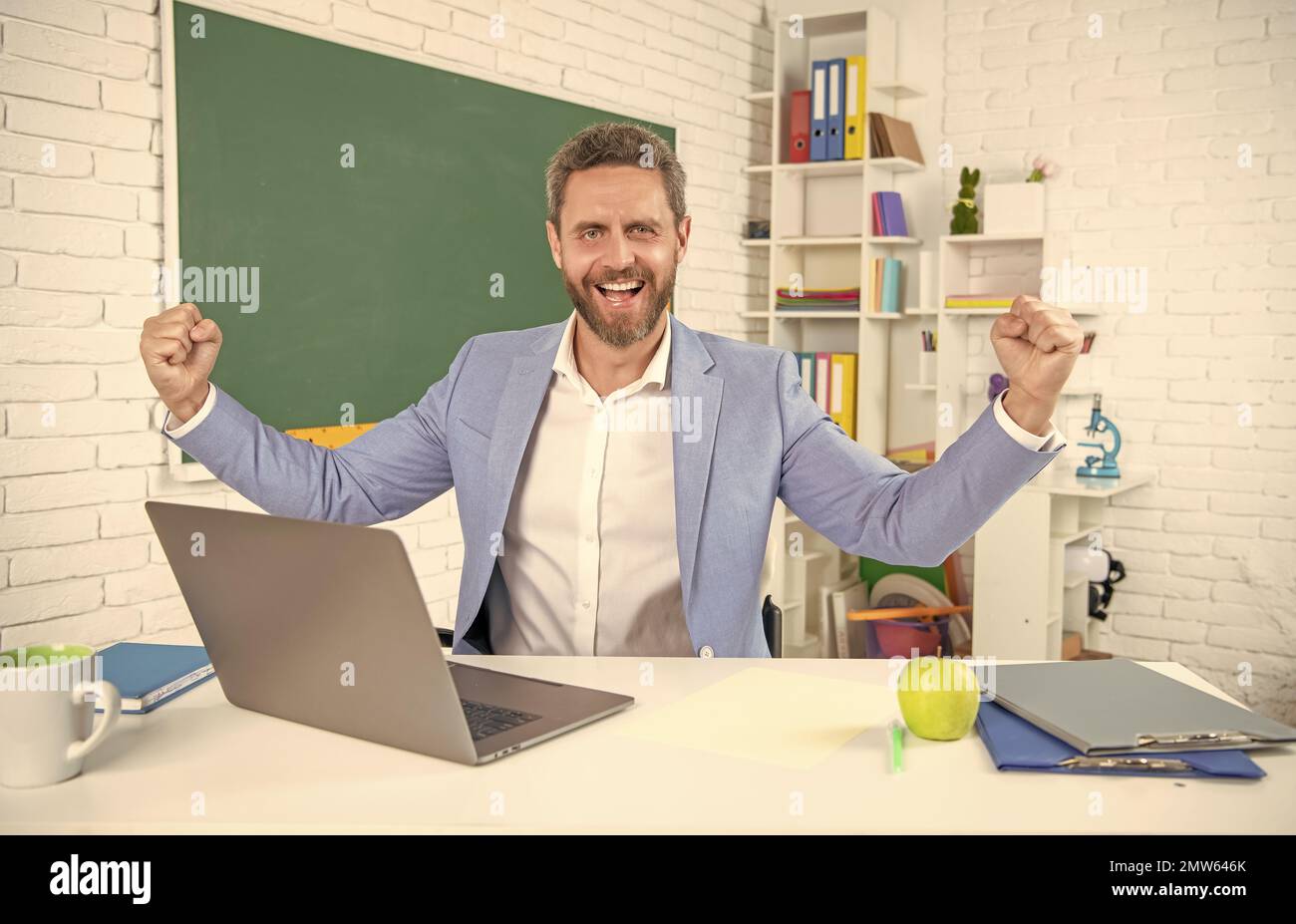 happy glad school teacher in classroom with computer at blackboard ...