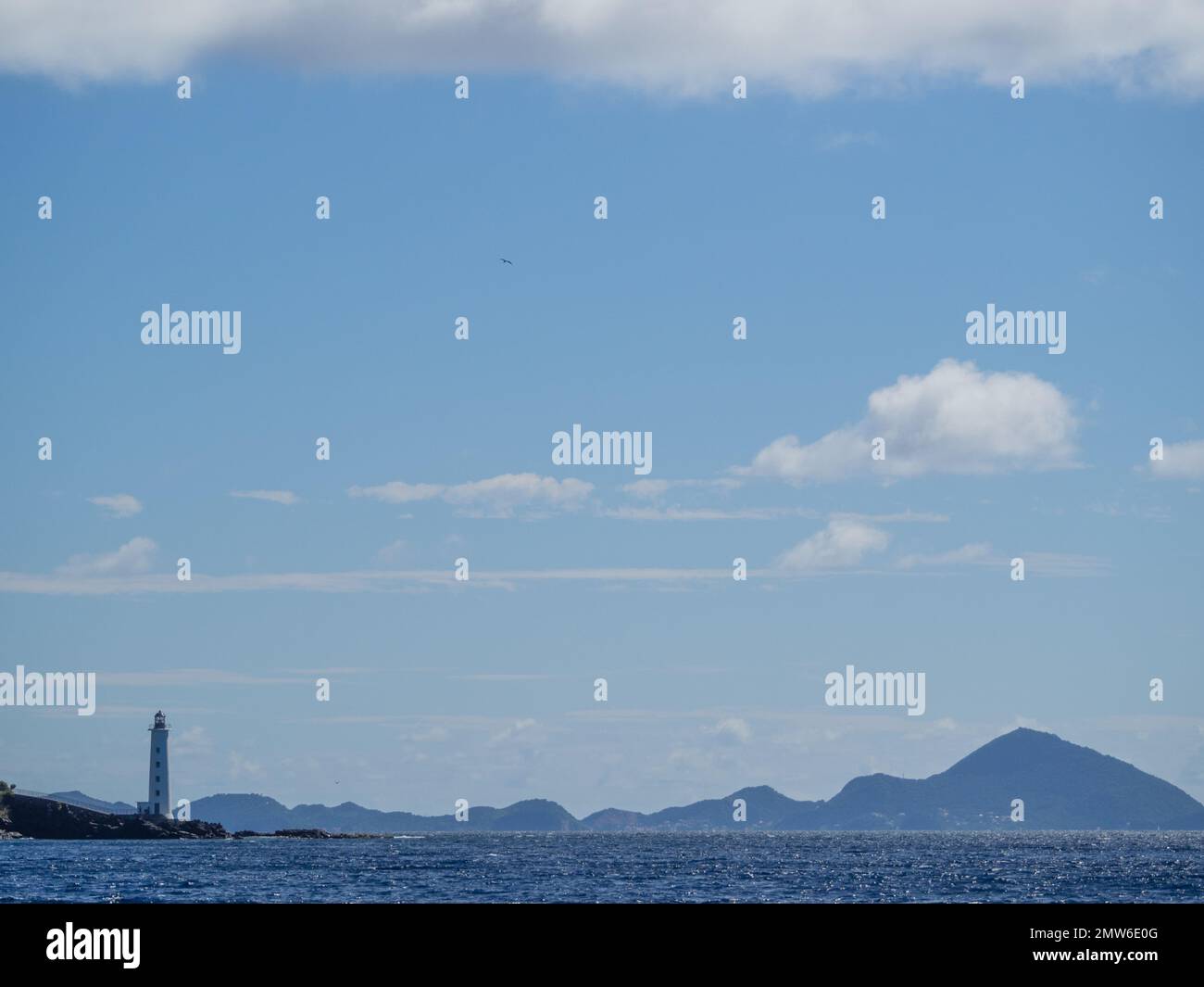 a view of Guadeloupe lighthouse on rocky outcrop on left, framed at top ...