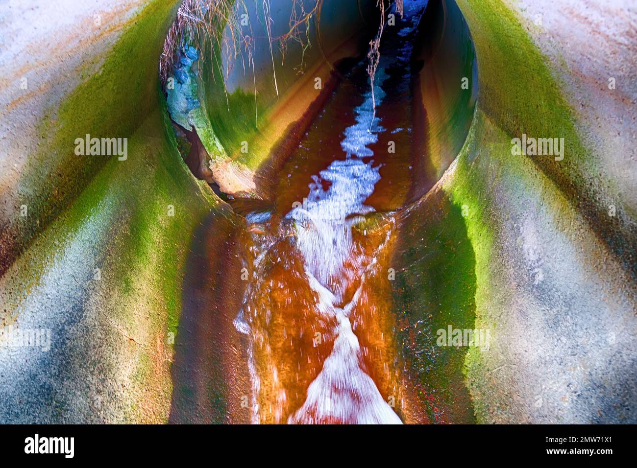 Brown swamp water full of organic substances flows down the pipe and ...