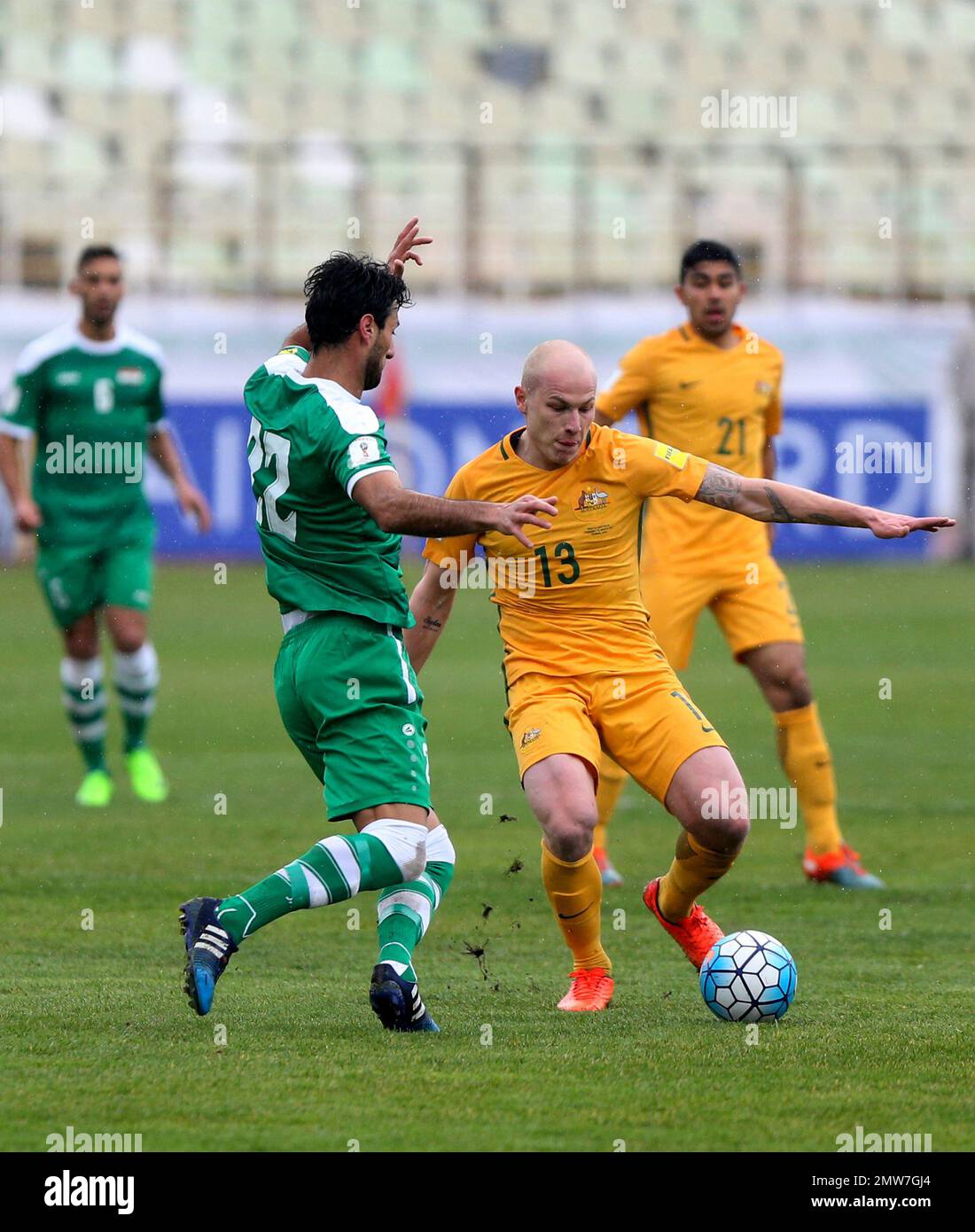 Australia's Aaron Mooy, right, plays the ball as he is followed by Iraq ...