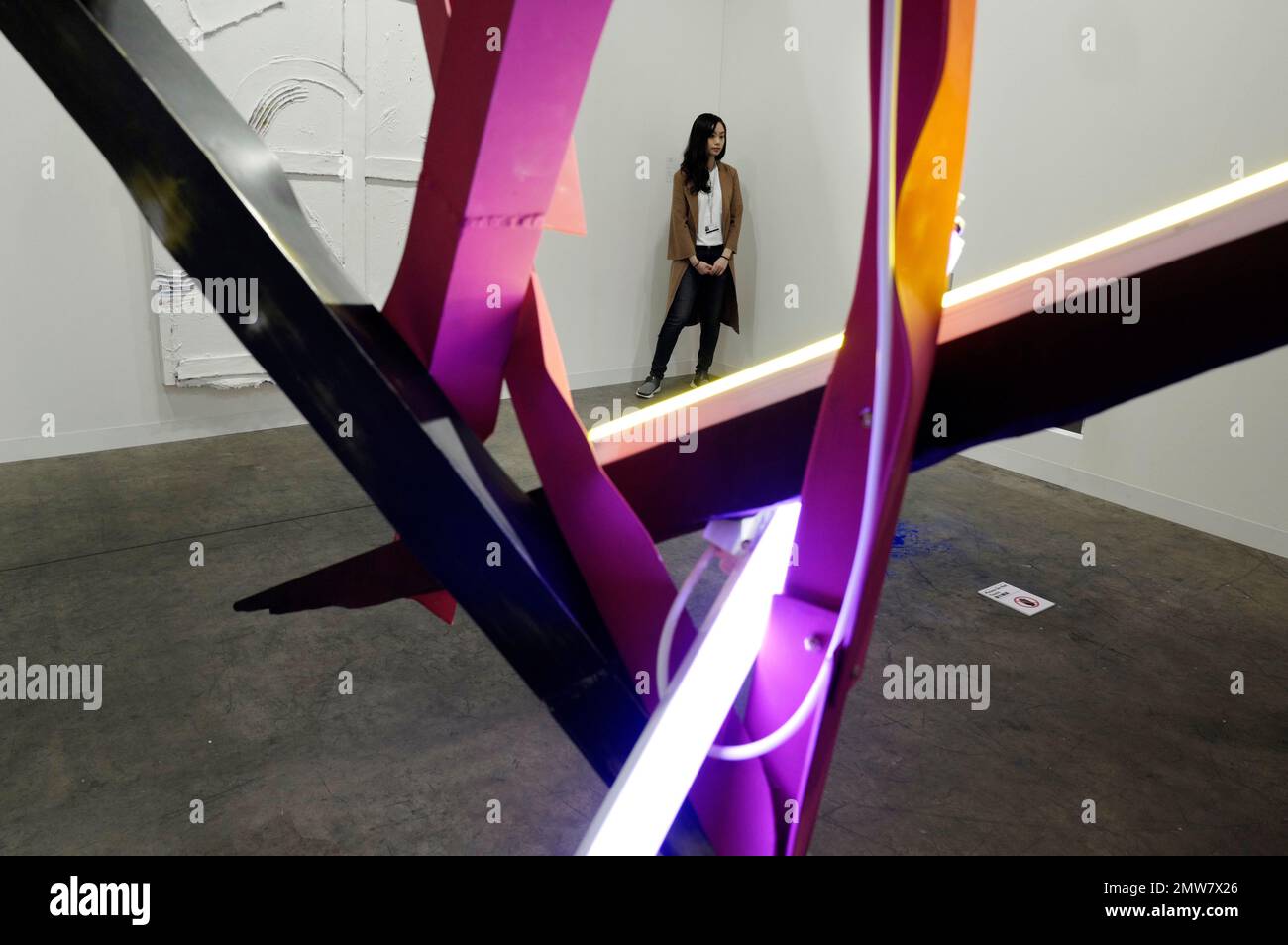 A woman stands in front of the artwork "Twisted Red Star" created by U ...