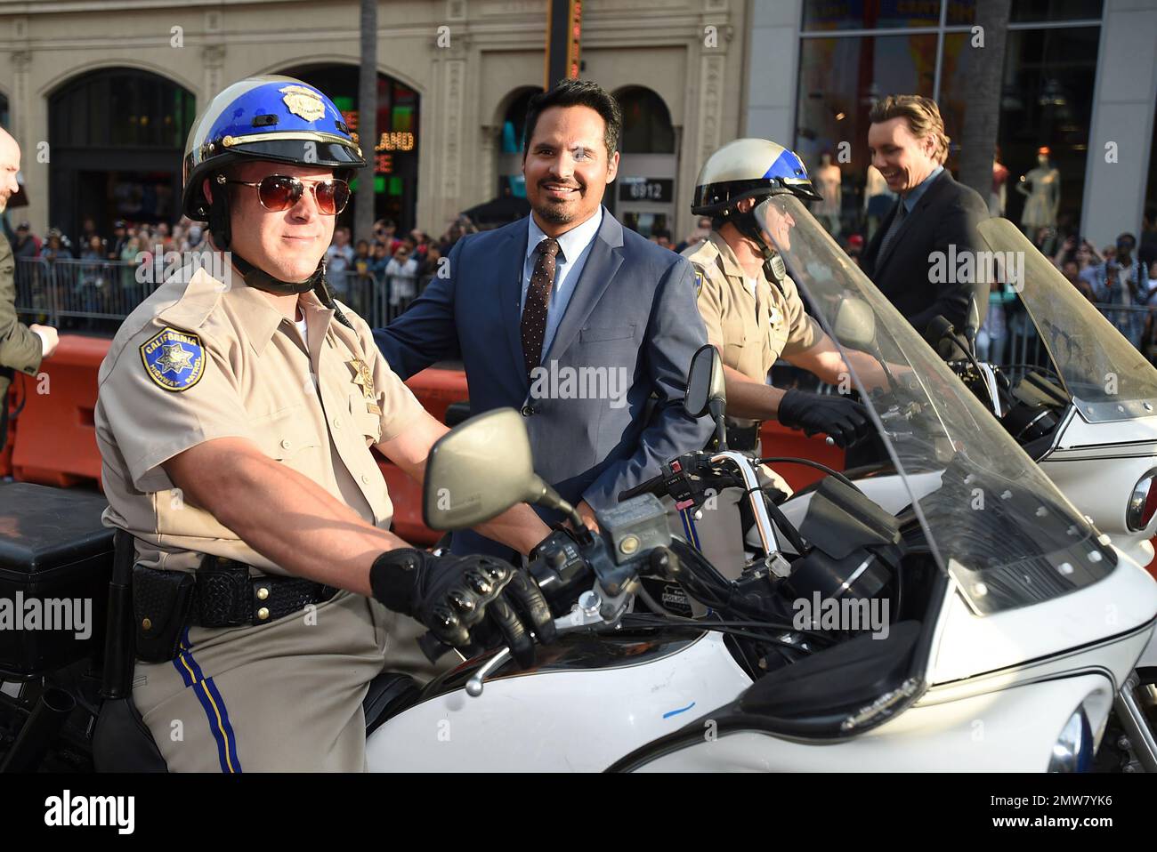 Actors dressed as police officers escort Dax Shepard, standing far ...