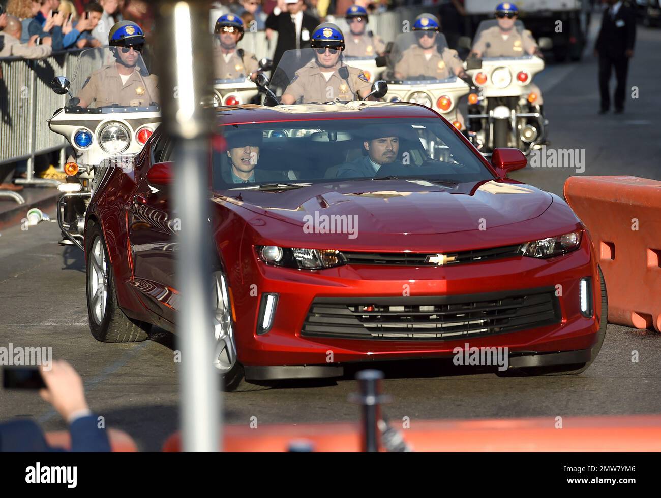 Actors dressed as police officers escort Dax Shepard, seated left, and ...