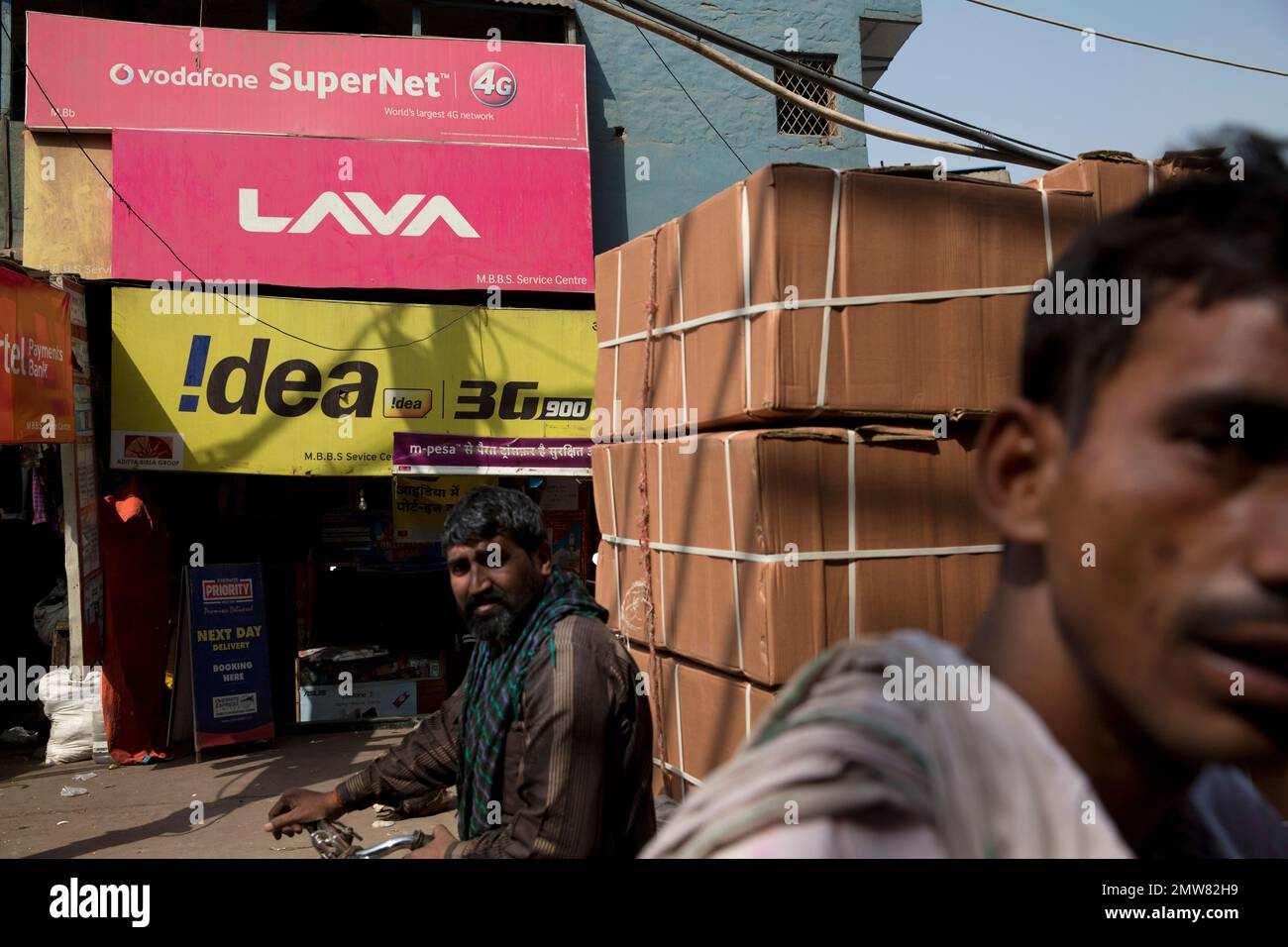 Indian workers walk past an advertisement of Idea Cellular in New Delhi ...