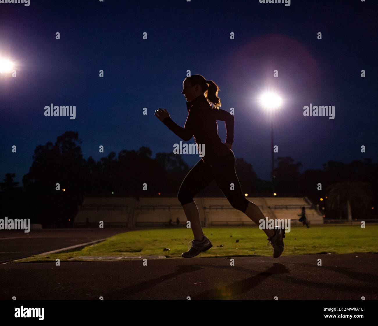 Female jogger running at track, night workout Stock Photo - Alamy