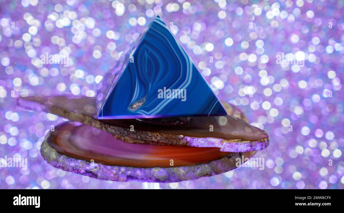 A quartz pyramid on natural mineral stones slices with a background of ...