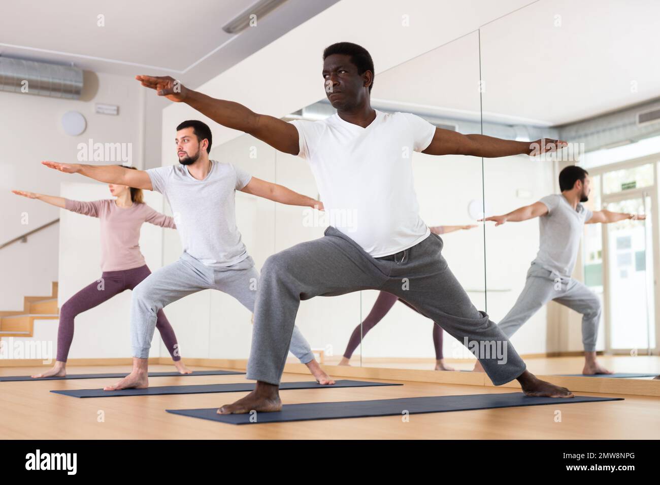 African American standing in Virabhadrasana during power yoga training ...