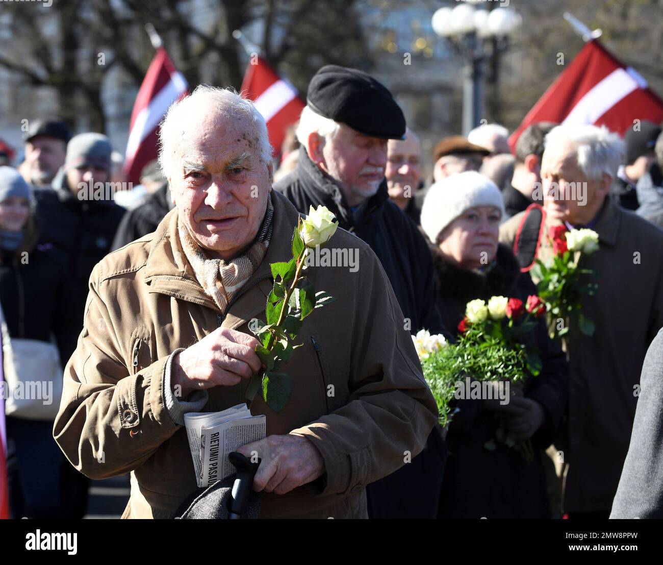 People carry Latvian flags and flowers as they march to the Freedom ...