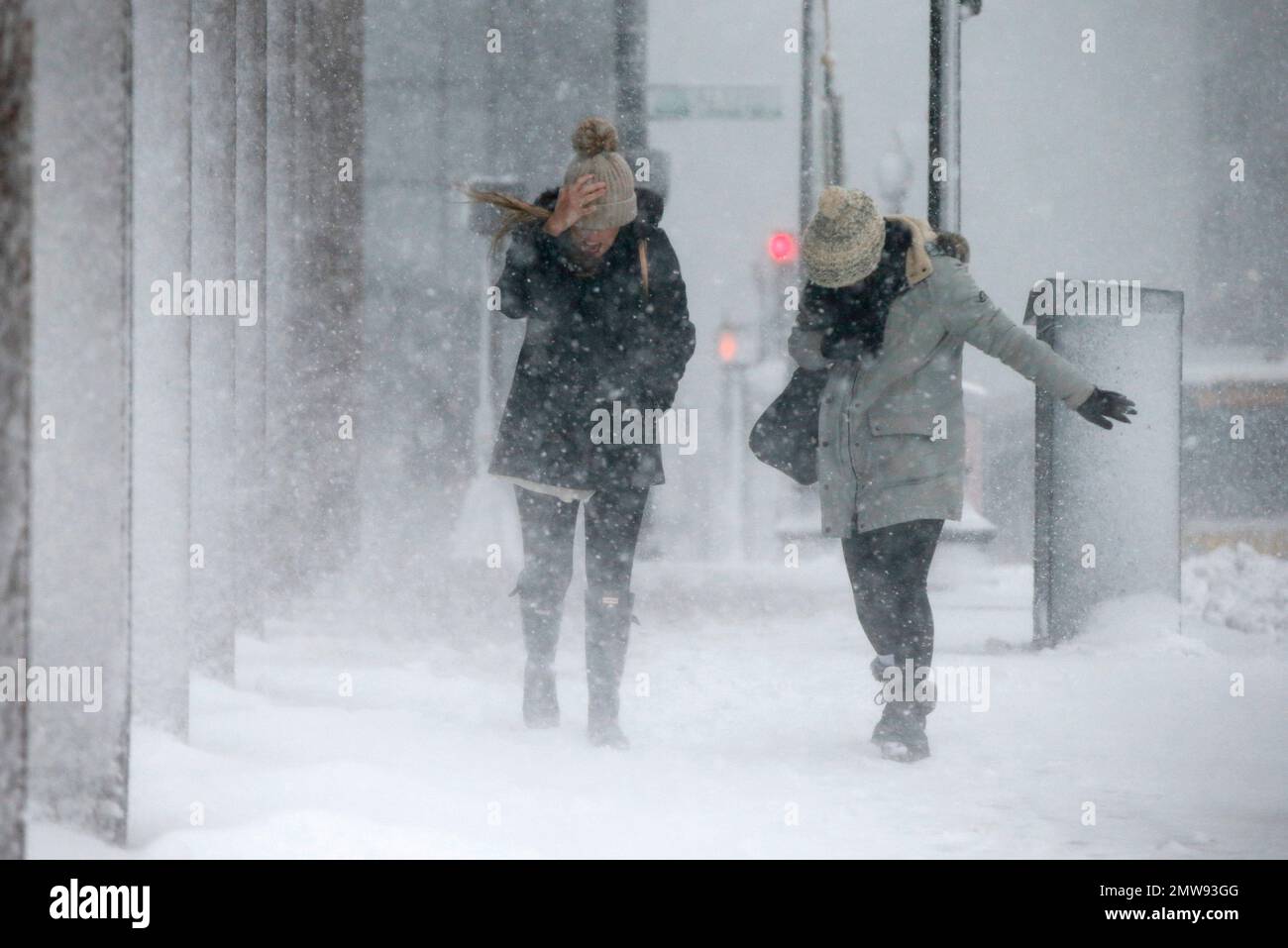 Two women struggle to walk in the blowing snow during a winter storm ...