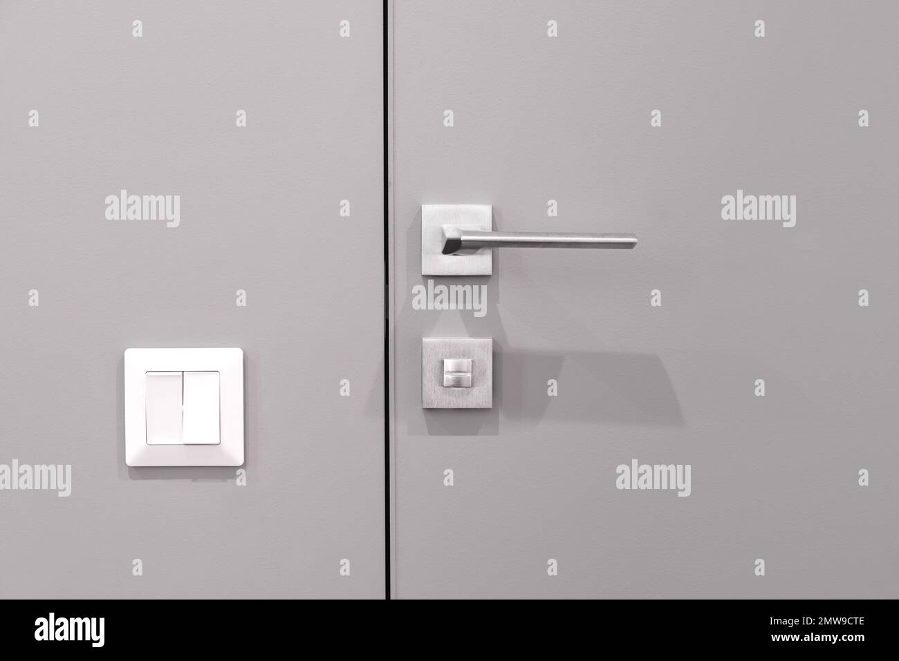 Closed hidden, gray interior door with a handle and a switch on the ...