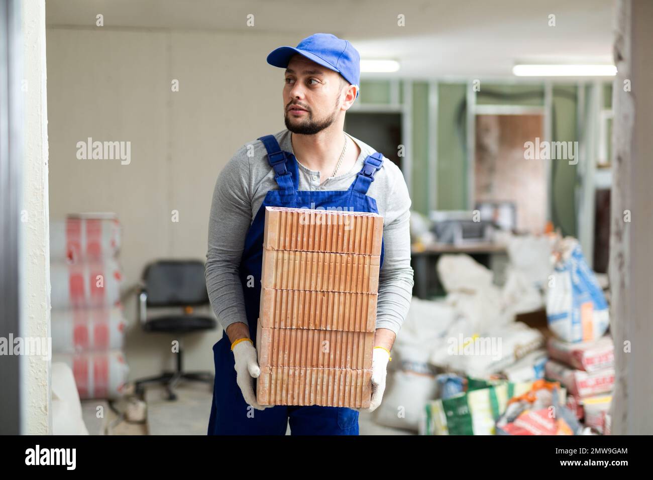 Portrait of a young builder carrying bricks Stock Photo - Alamy