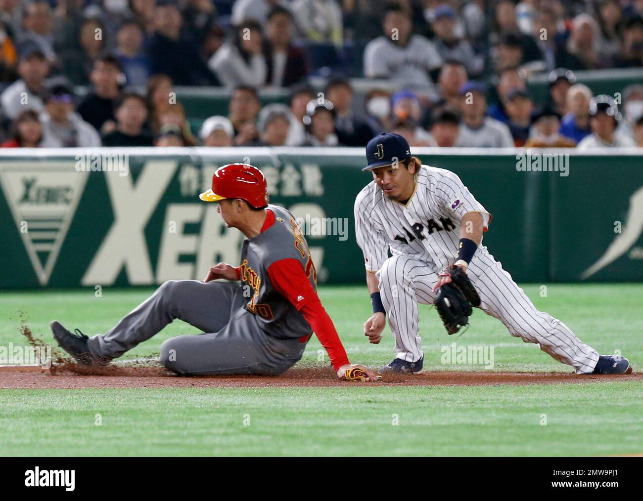 China's Chu Fujia, left, tags up from second past Japan's third baseman ...