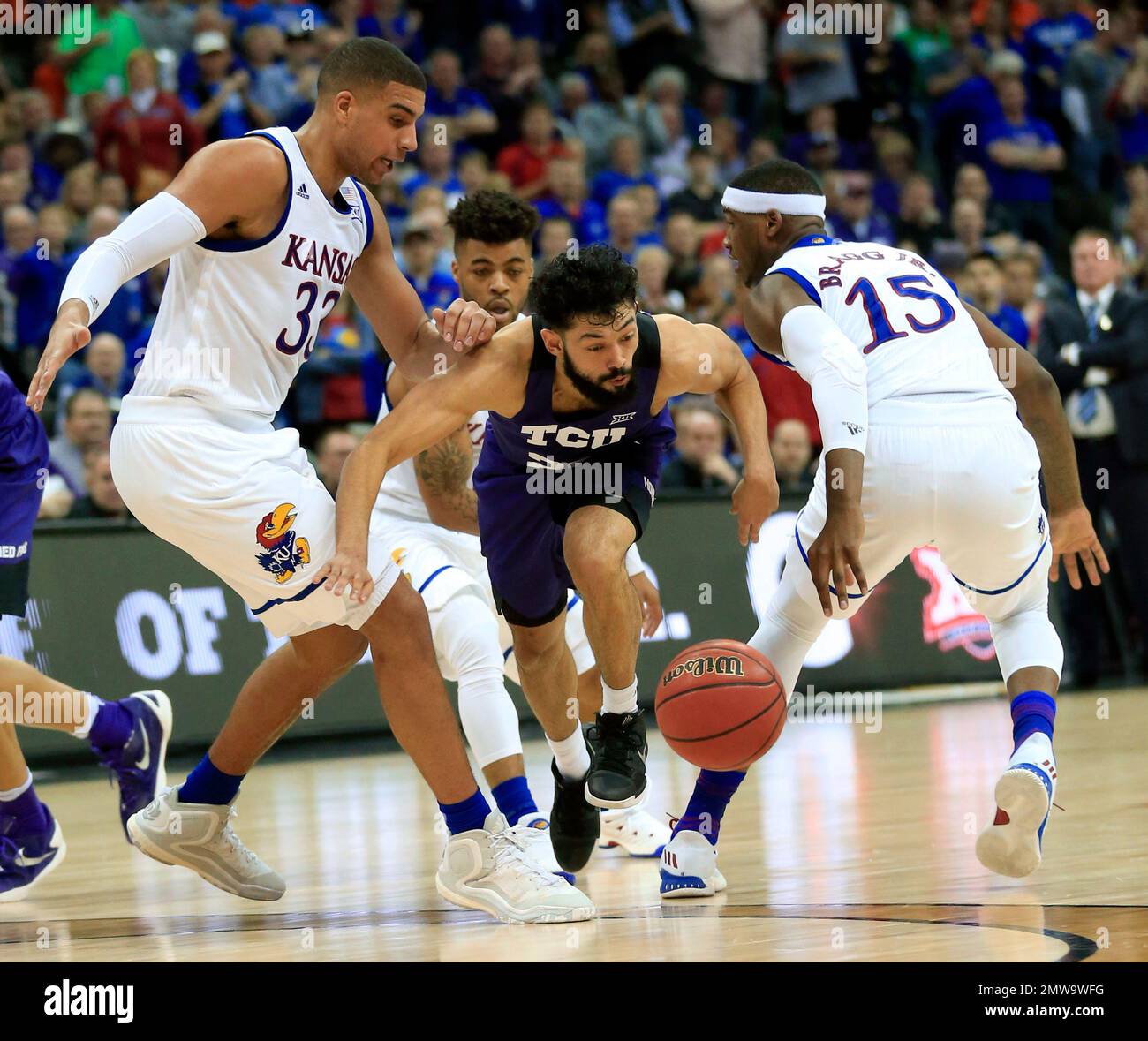 TCU guard Alex Robinson (25) splits Kansas defenders Landen Lucas (33 ...