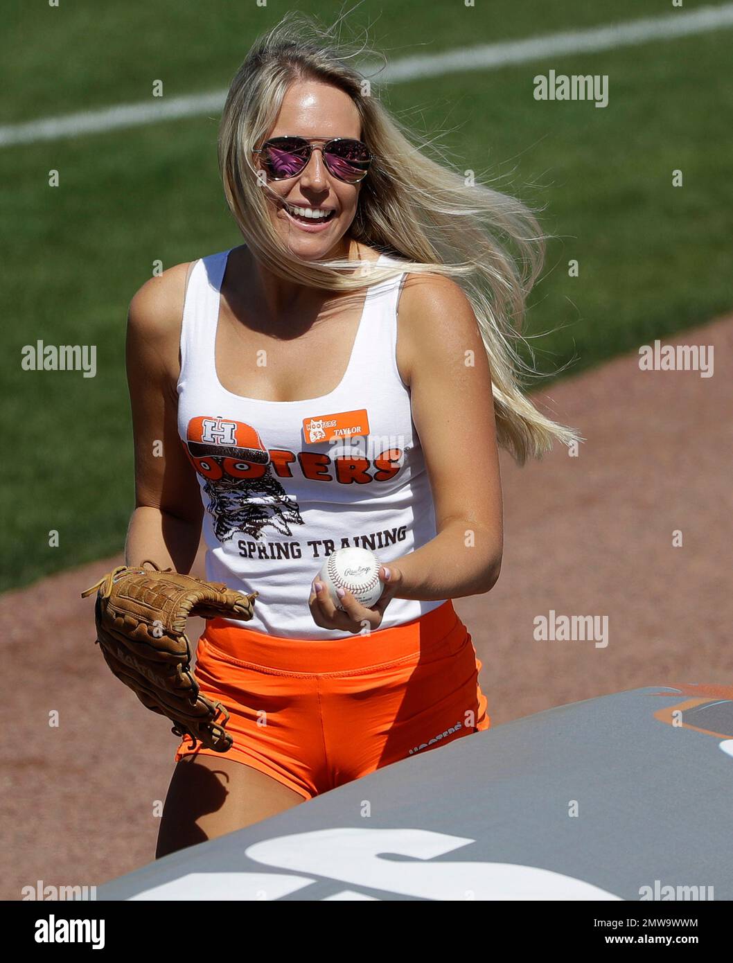 A Hooters restaurant ball girl gives a baseball to a fan during the ...