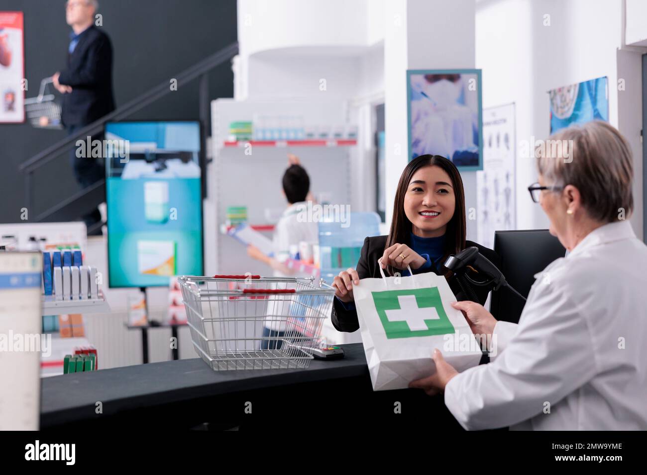 Asian woman buying supplements at pharmacy store counter desk, taking ...