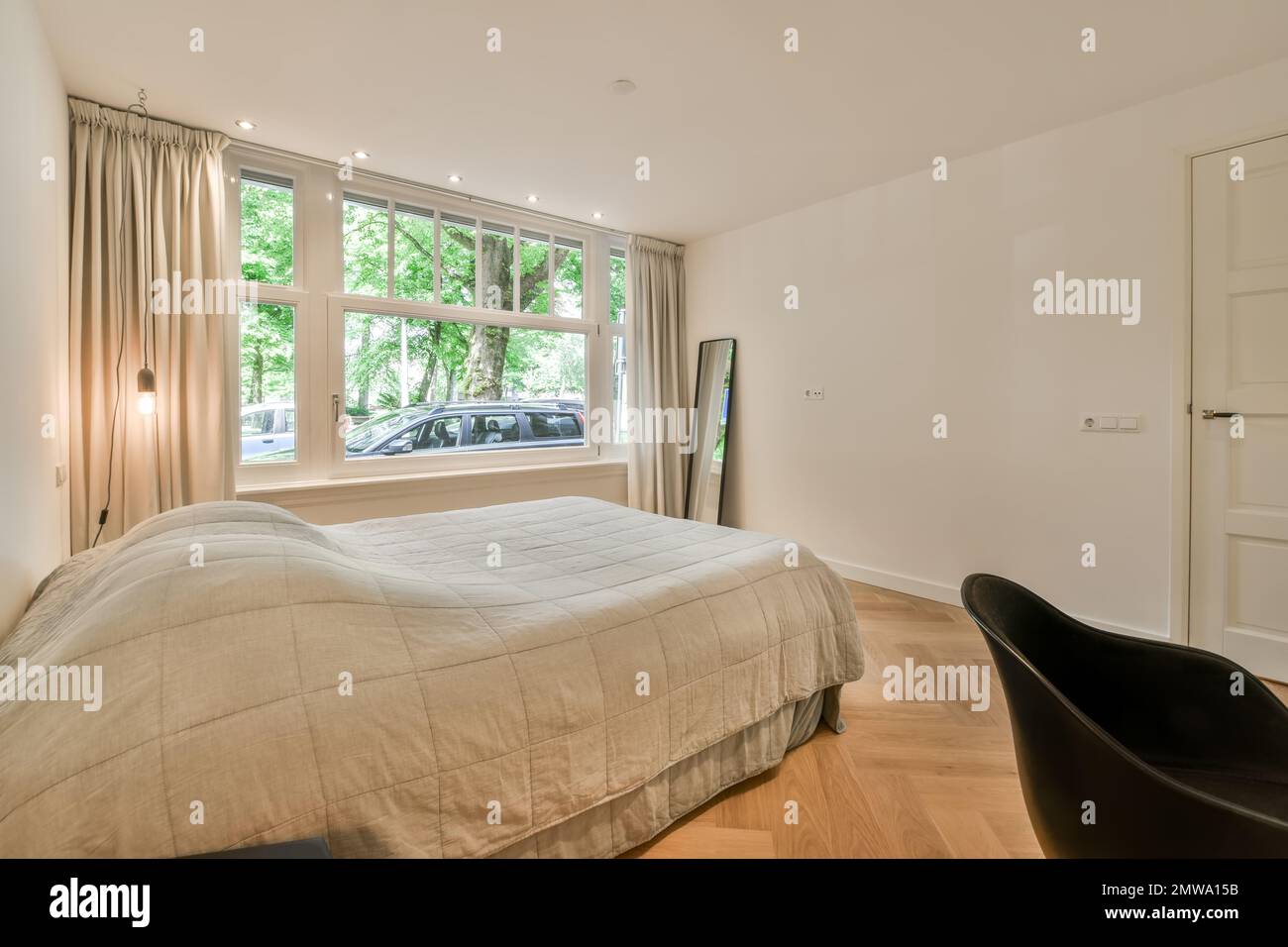 a bedroom with a bed, chair and window looking out onto the street in ...