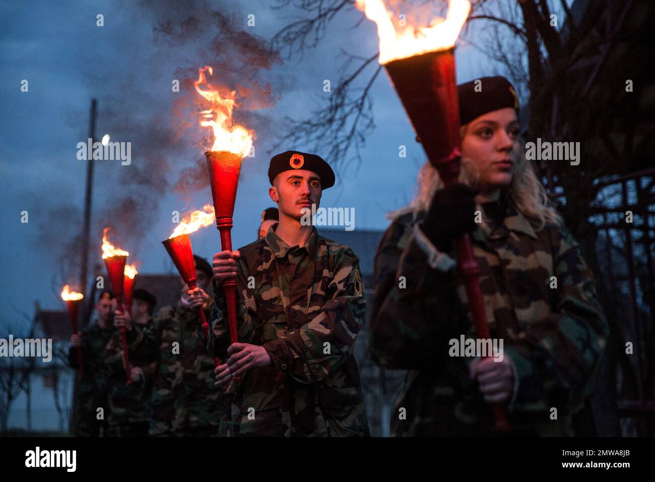 Kosovo Albanians in KLA uniforms hold torches during a bonfire ceremony ...