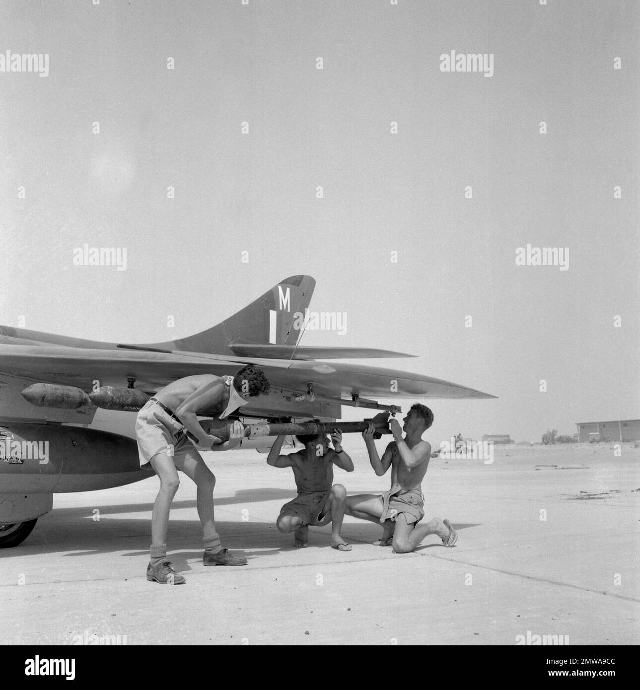British airmen load a rocket powered missile under the wing of a Hawker ...
