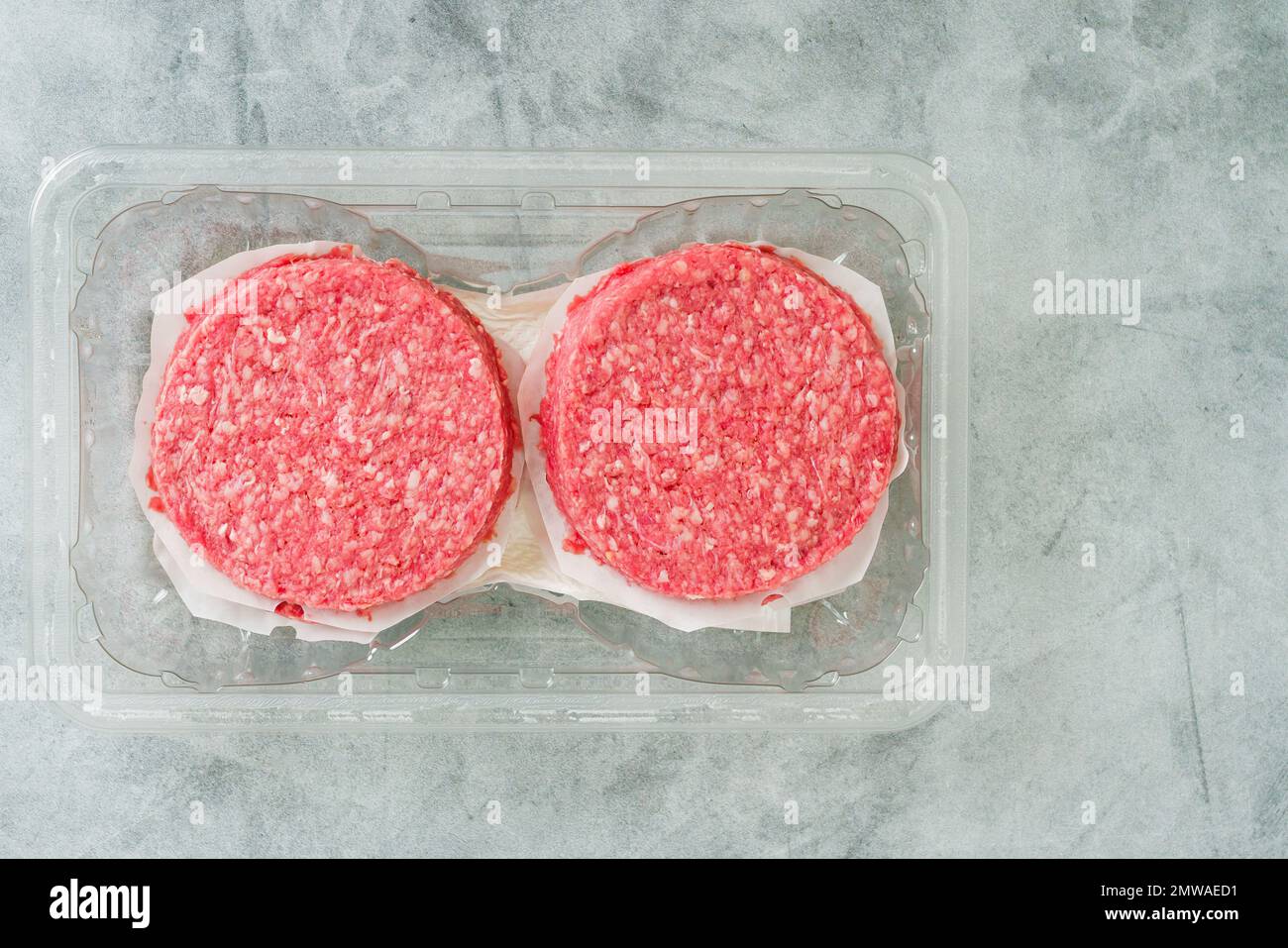 Burger patties in plastic container close-up. Fresh raw burger patties ...