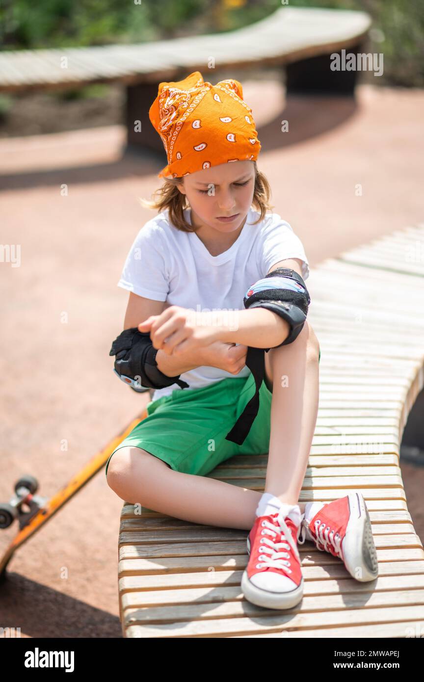 Focused skateboarder putting on the protective gear Stock Photo - Alamy