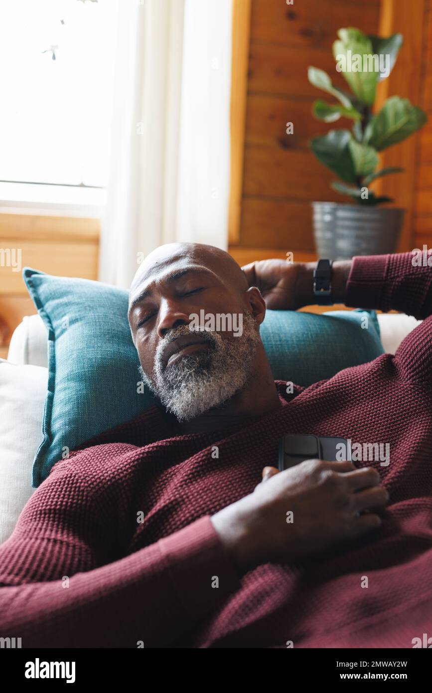 Tired african american man sleeping on sofa in log cabin, copy space ...