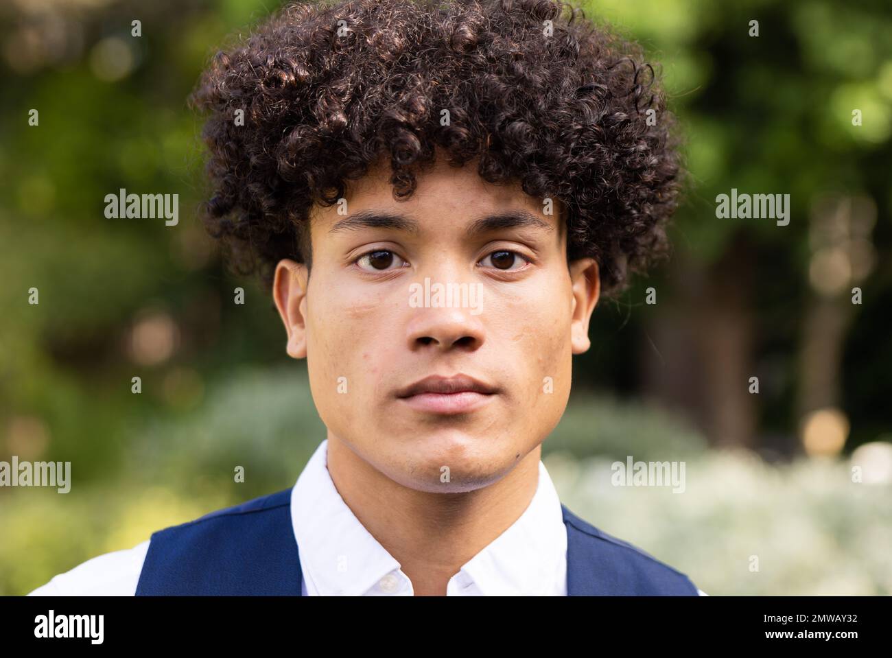 Portrait of biracial groom with curly hair looking to camera in garden Stock Photo - Alamy