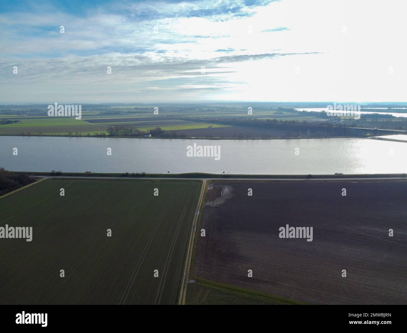 An aerial view of calm lake water through the green agricultural fields ...