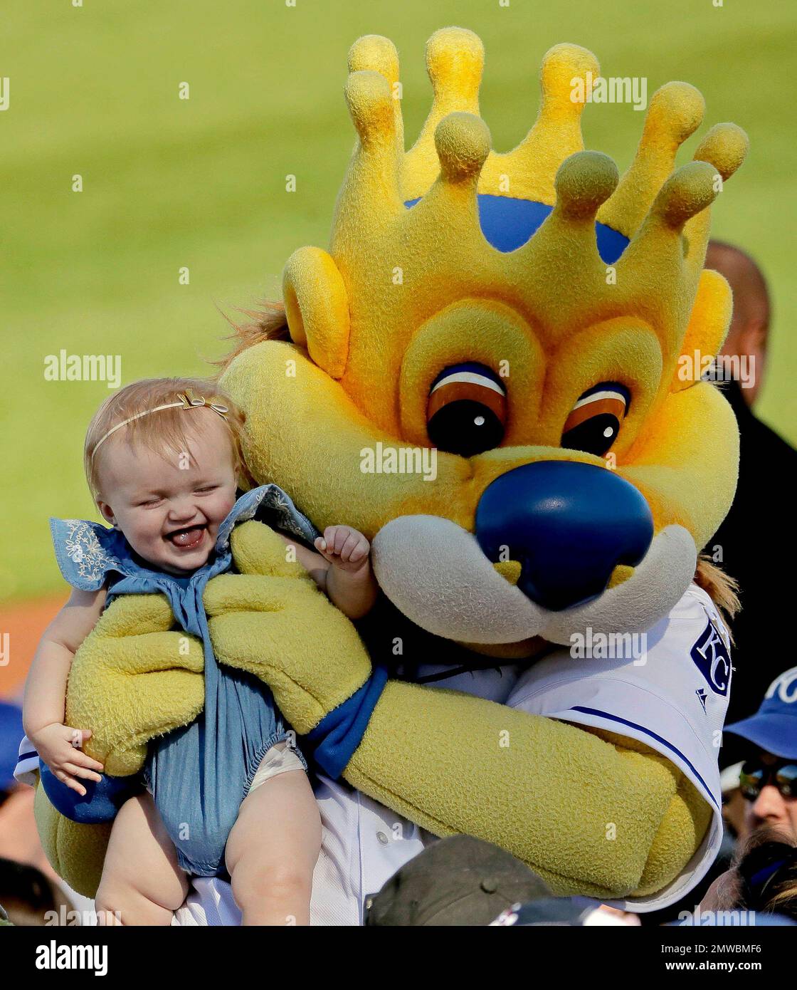 Kansas City Royals mascot Sluggerrr holds a baby in the crowd during ...
