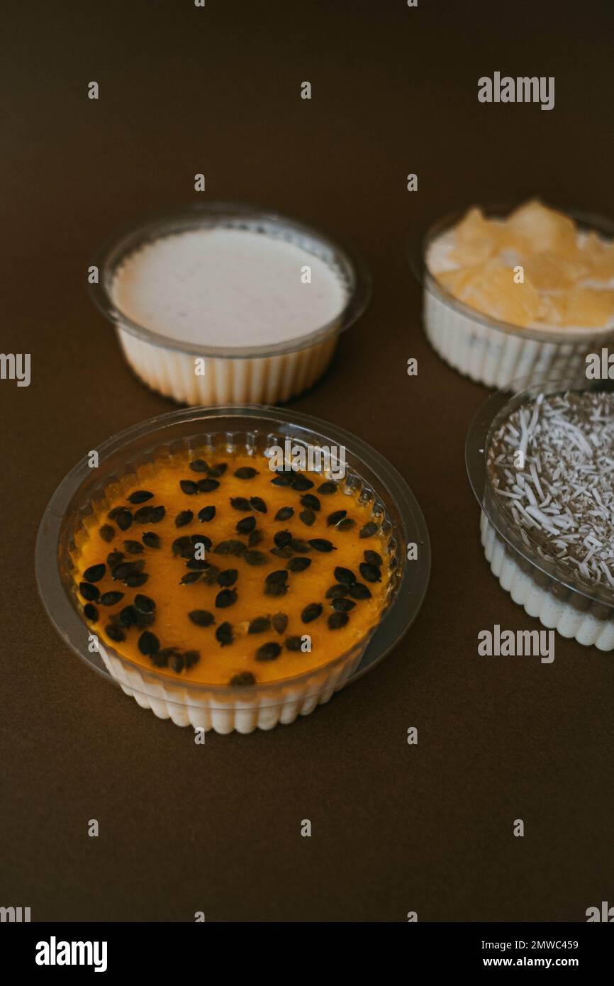 A vertical shot of plastic bowls of various creamy pudding on a brown ...