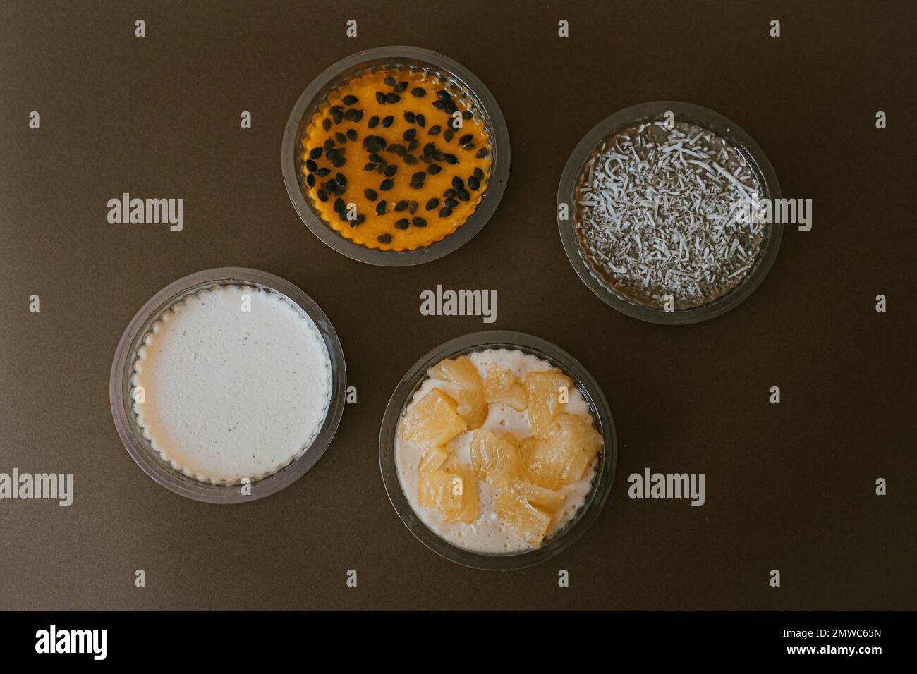 A high angle shot of plastic bowls of various creamy pudding on a brown ...